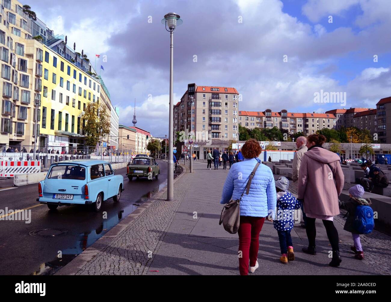 Two (2) old East German Trabant cars passing people walking in front of the Memorial to the ...