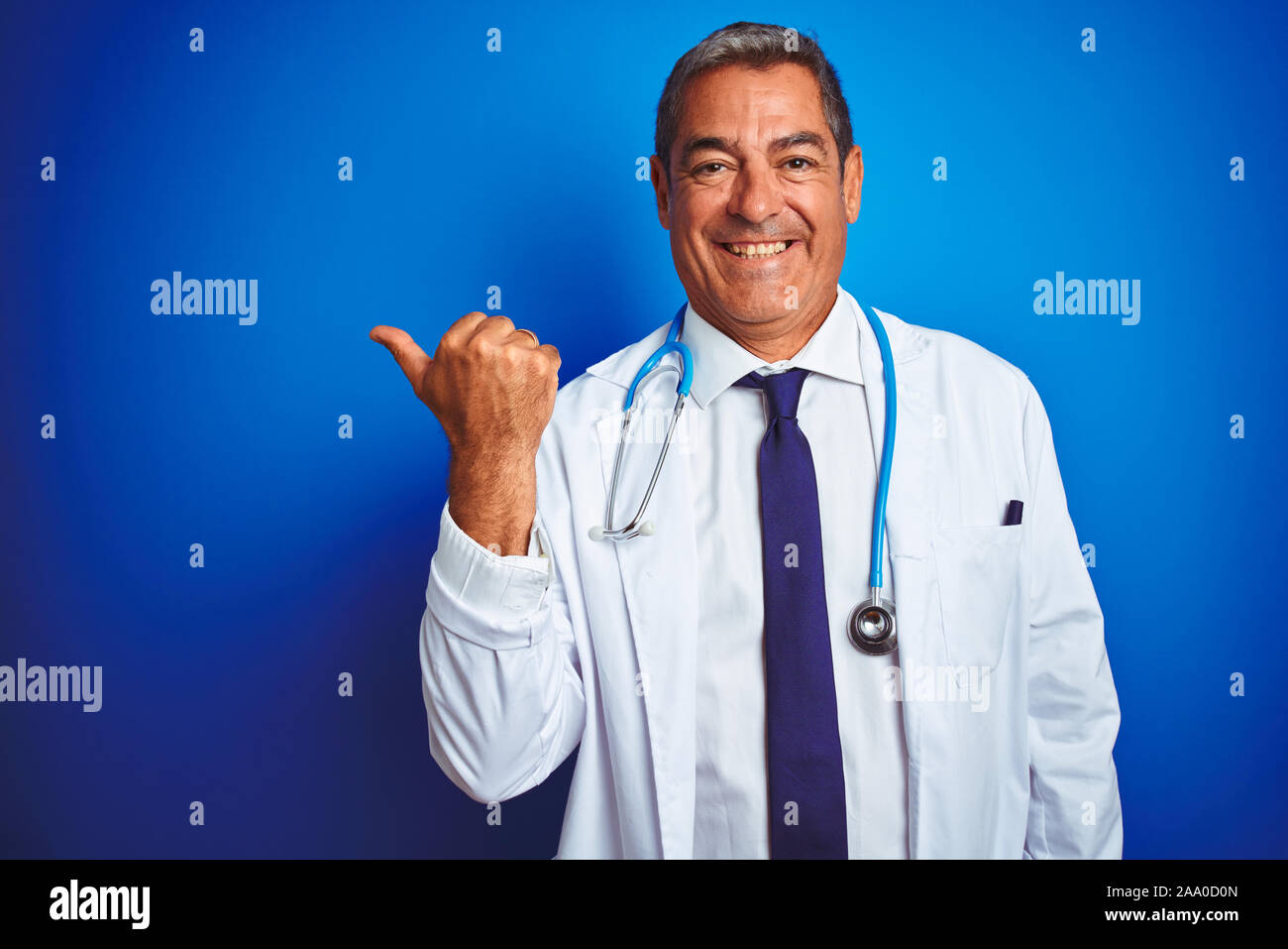 Handsome middle age doctor man wearing stethoscope over isolated blue ...