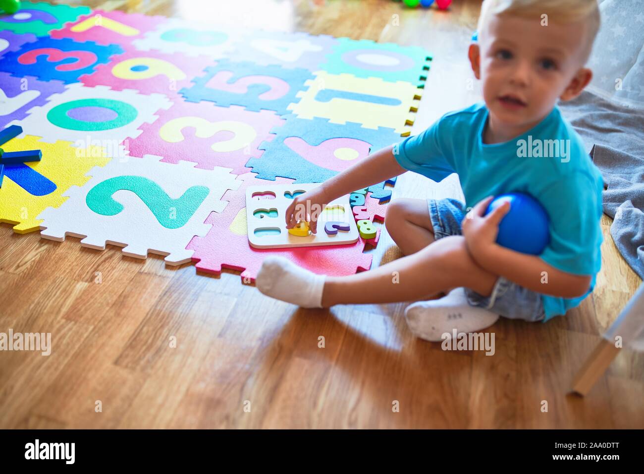 Young caucasian kid playing placing numbers at kindergarten ...