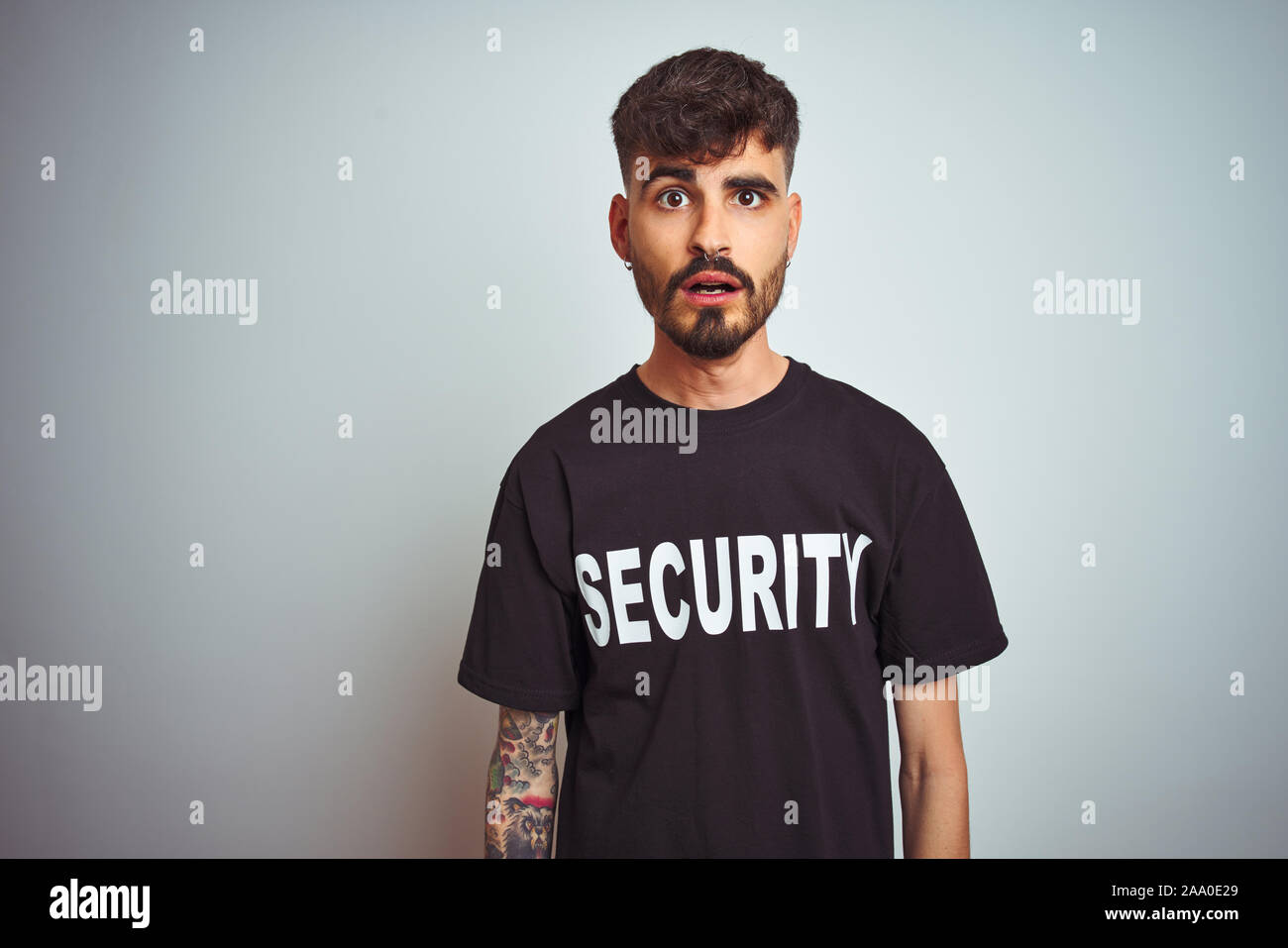 Young safeguard man with tattoo wering security uniform over isolated ...