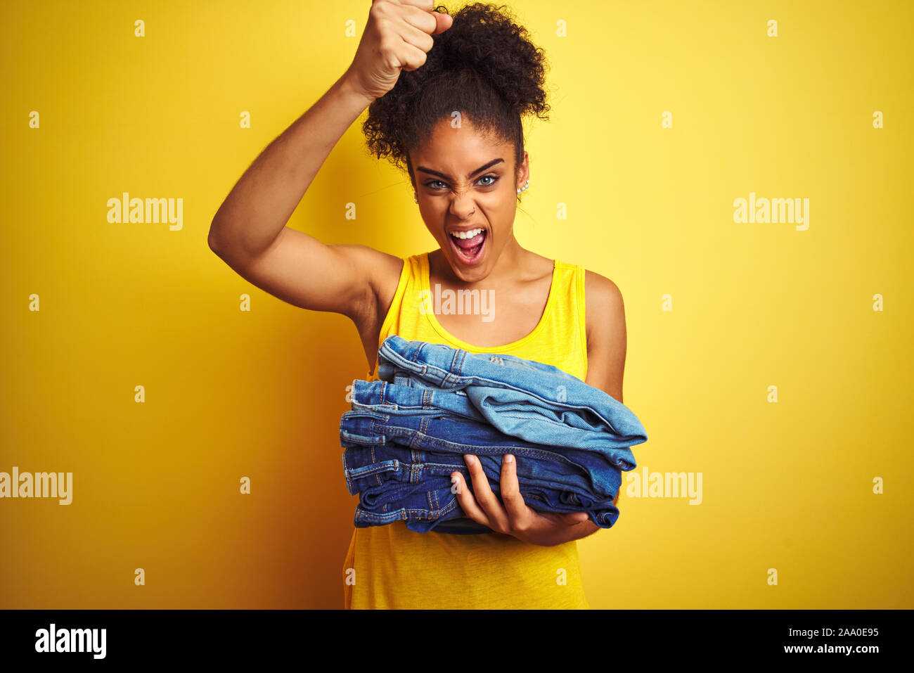 Young african american woman holding stack of jeans over isolated ...