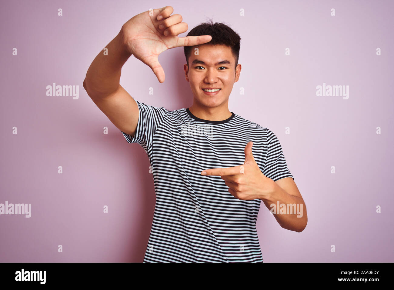 Young asian chinese man wearing striped t-shirt standing over isolated ...