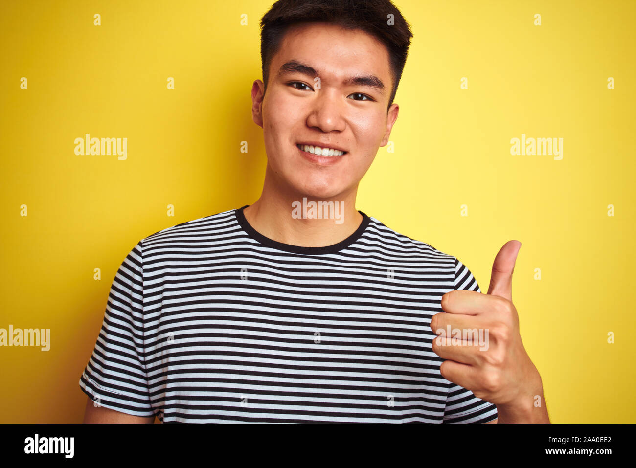 Young Asian Chinese Man Wearing Striped T Shirt Standing Over Isolated