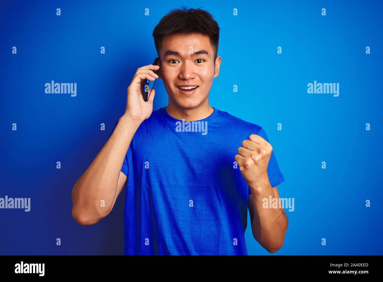 Young asian chinese man talking on the smartphone standing over ...