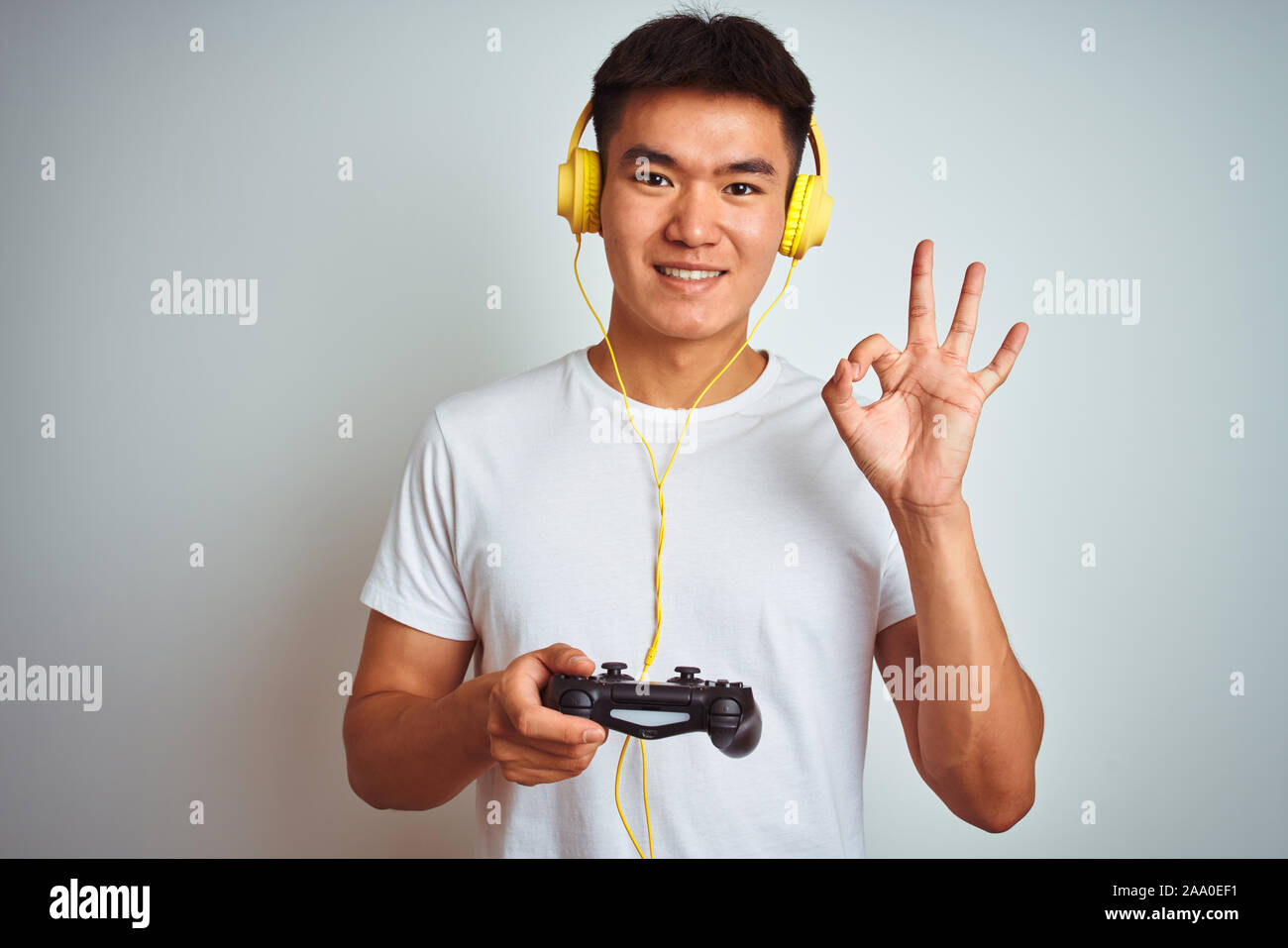 Young asian chinese gamer man playing video game standing over isolated ...