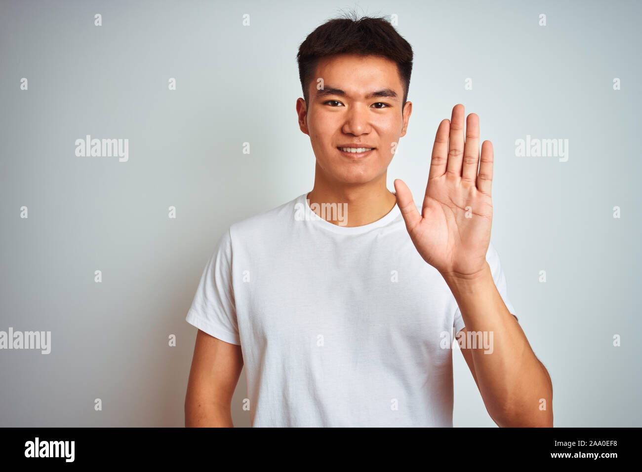 Young asian chinese man wearing t-shirt standing over isolated white ...