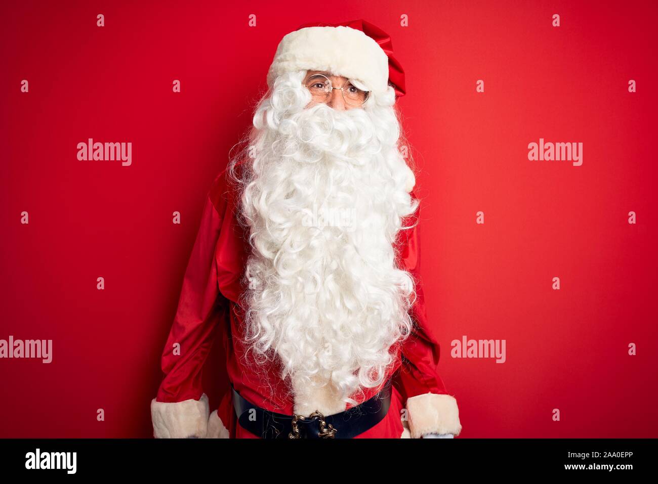 Middle age handsome man wearing Santa costume standing over isolated ...