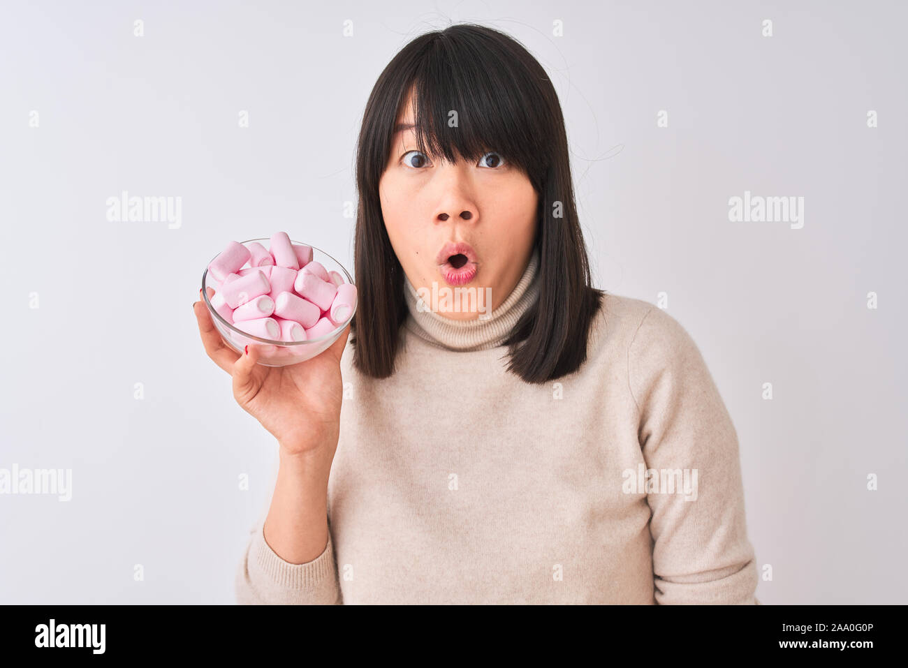 Beautiful Chinese woman holding bowl with marshmallows over isolated ...