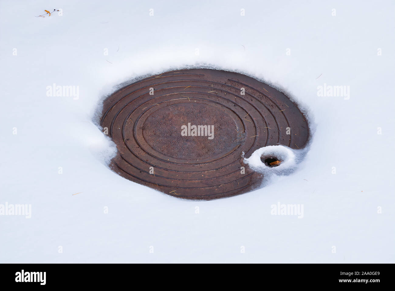 Sewer manhole on a city sidewalk covered with white snow Stock Photo ...