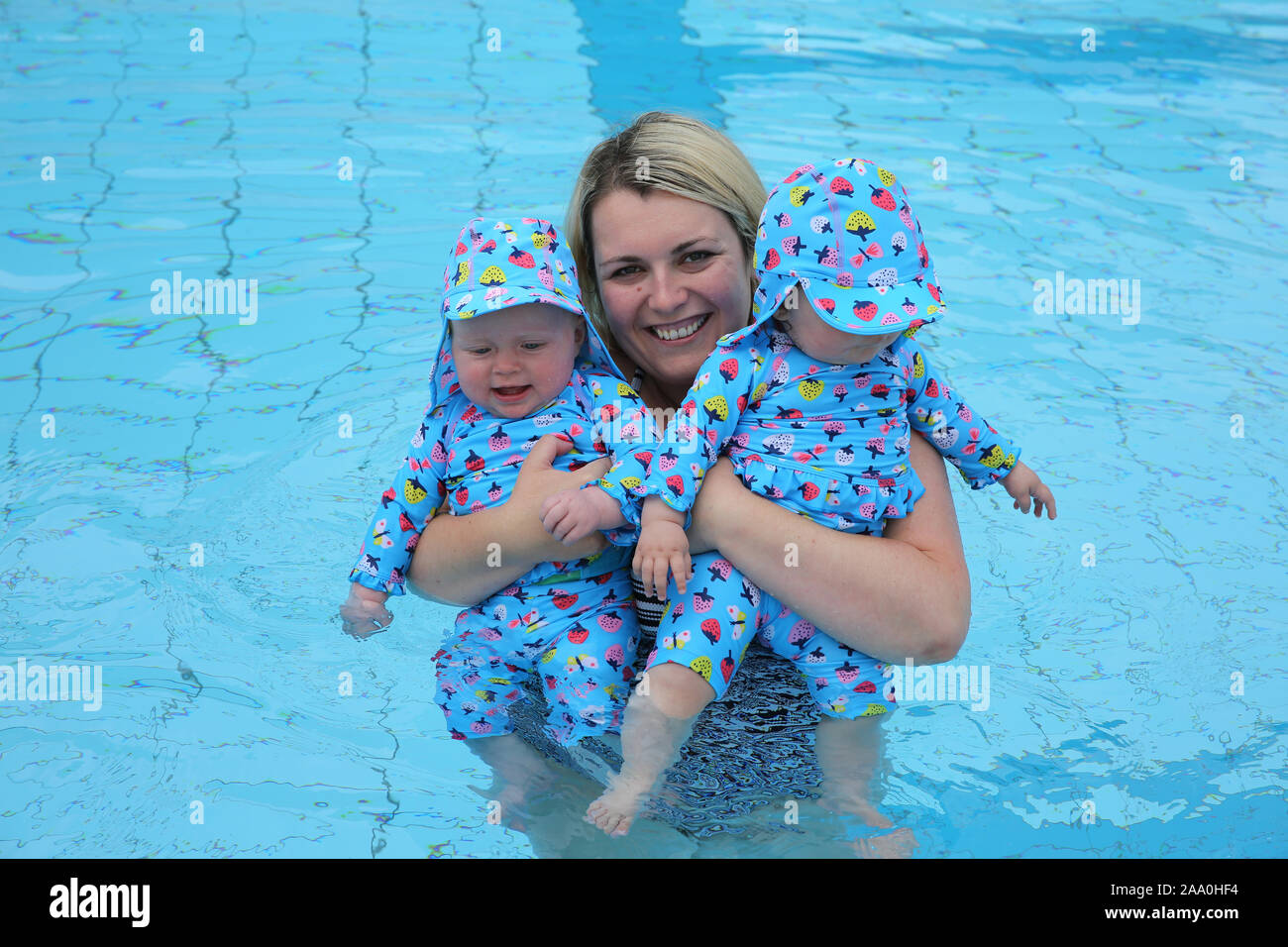 Mum with non-identical twins in swimming pool Stock Photo - Alamy