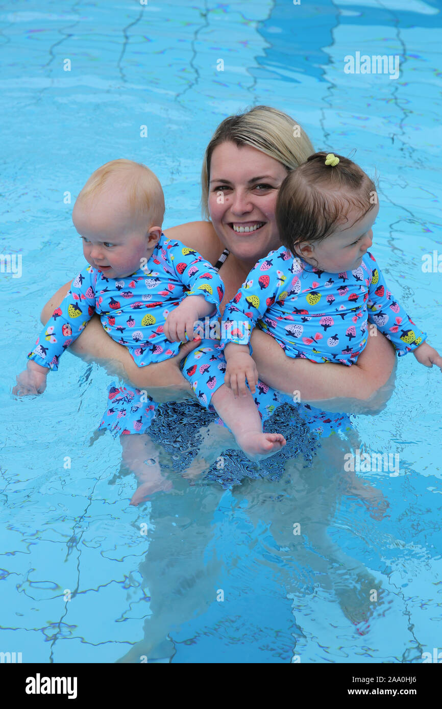 Mum with non-identical twins in swimming pool Stock Photo - Alamy