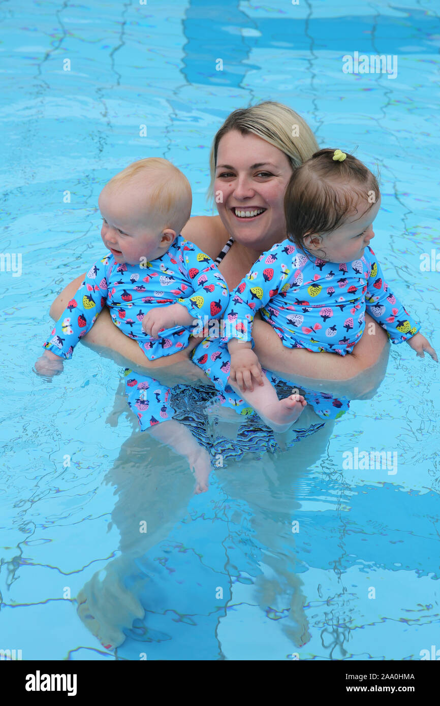 Mum with non-identical twins in swimming pool Stock Photo - Alamy