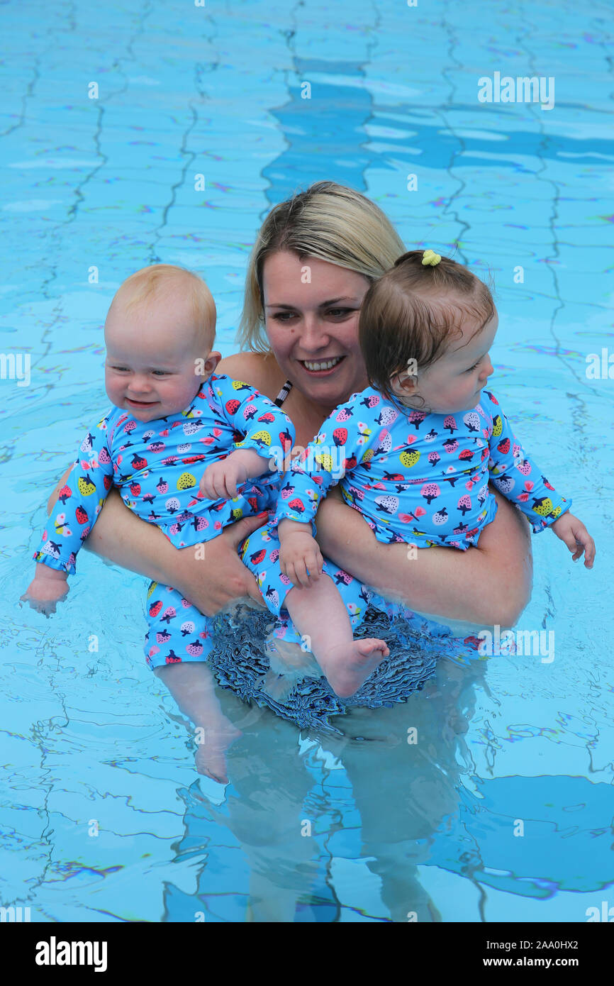 Mum with non-identical twins in swimming pool Stock Photo - Alamy