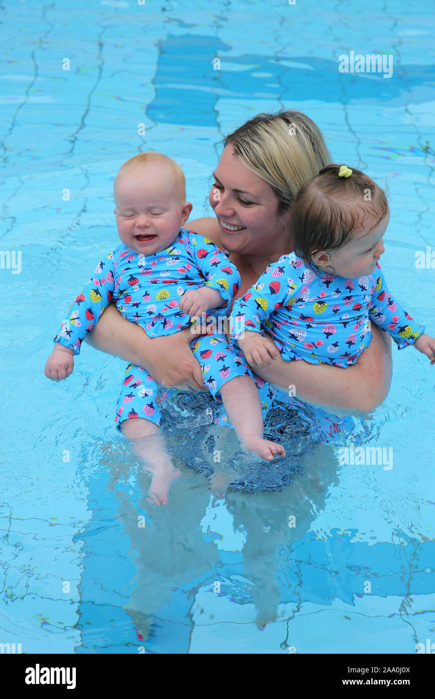 Mum with non-identical twins in swimming pool Stock Photo - Alamy