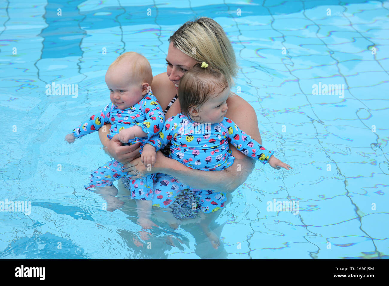 Mum with non-identical twins in swimming pool Stock Photo - Alamy