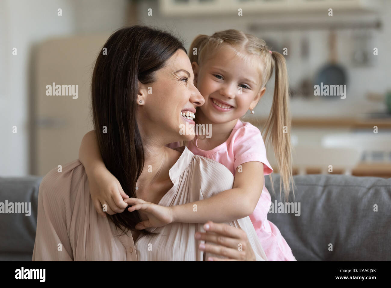Preschool girl cuddling from back smiling young mother Stock Photo - Alamy