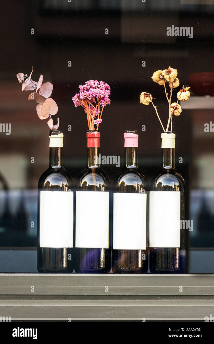 Four wine bottles with white label, decorated with flowers on top view ...