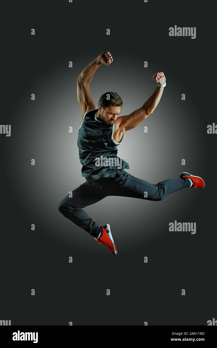 joyful athletic build man jumping on air on a black background ...