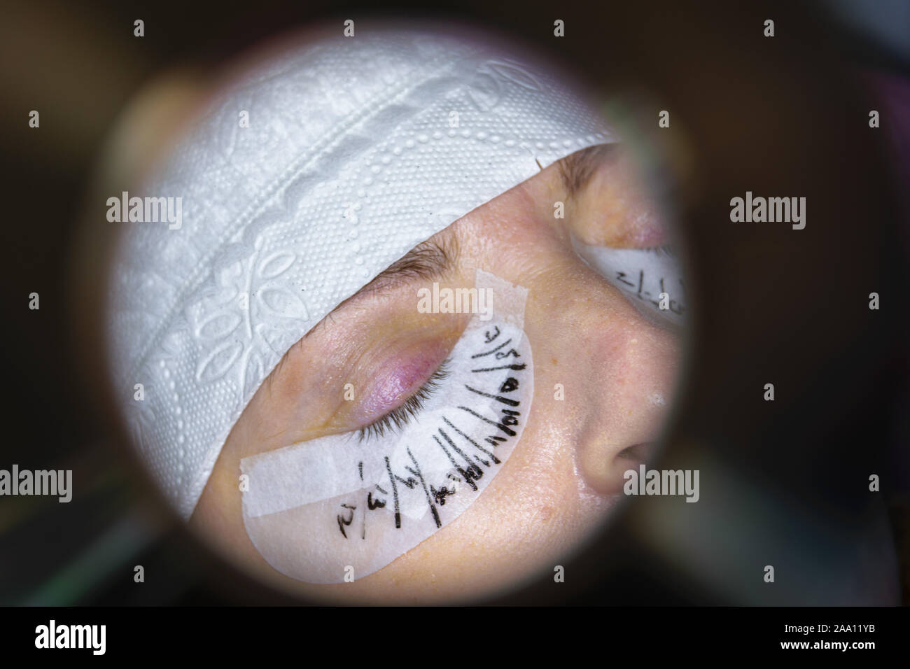 Extension of long eyelashes in a beauty salon. Wizard combing eyelash ...