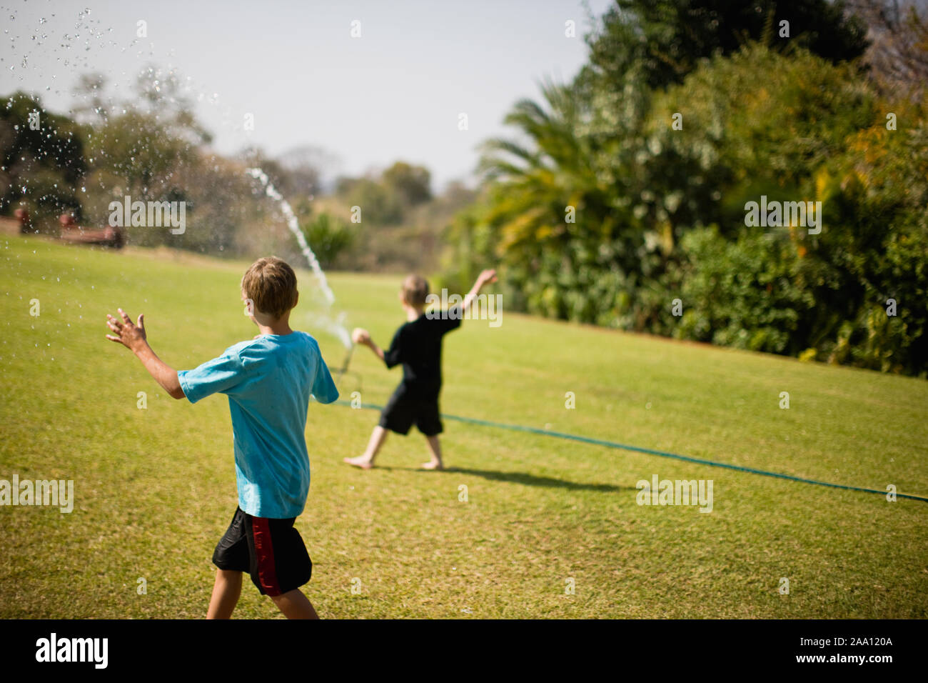 Two kids playing water sprinkler hi-res stock photography and images ...