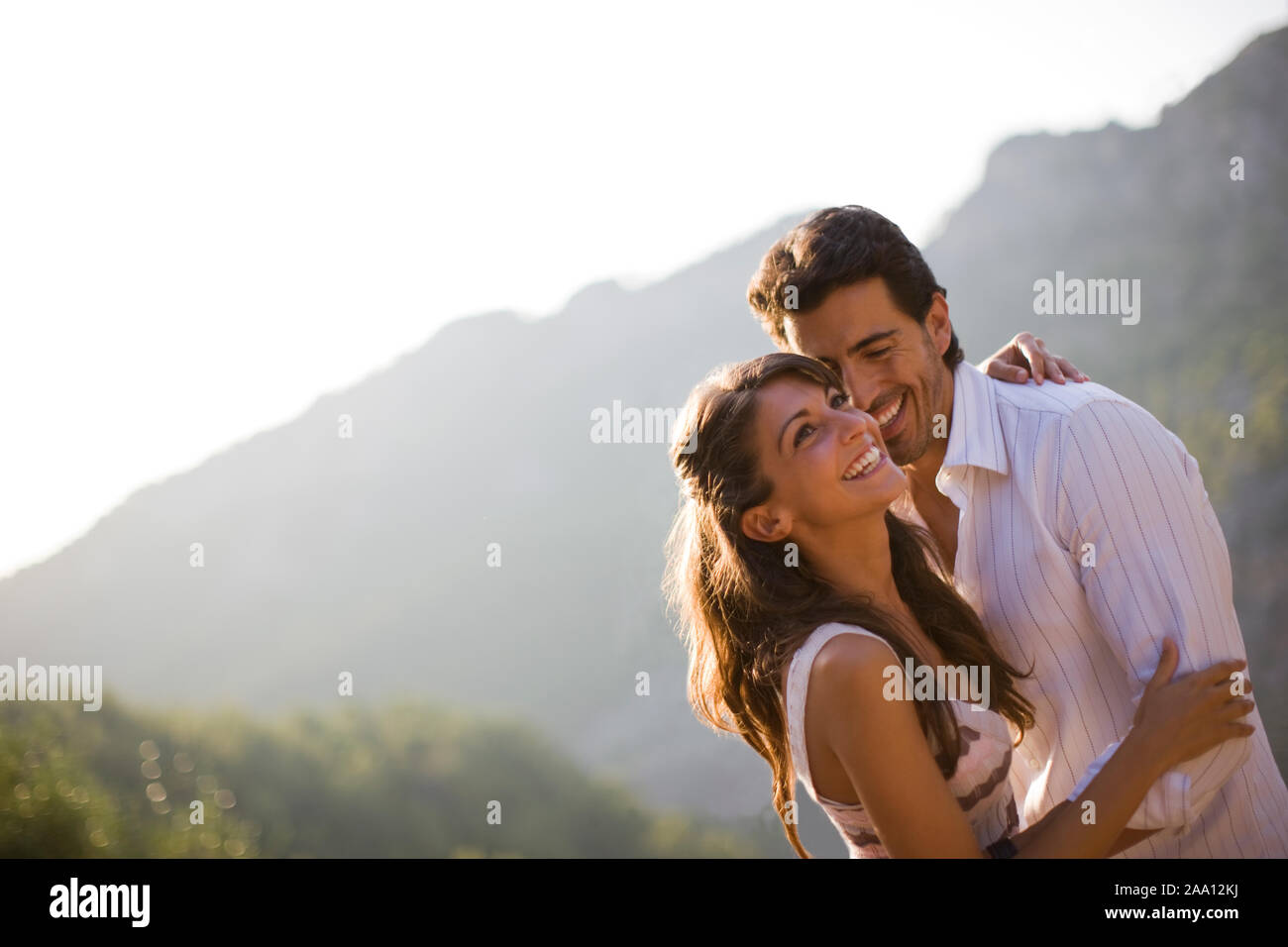 Mid adult couple hugging while walking on a country lane at sunset ...