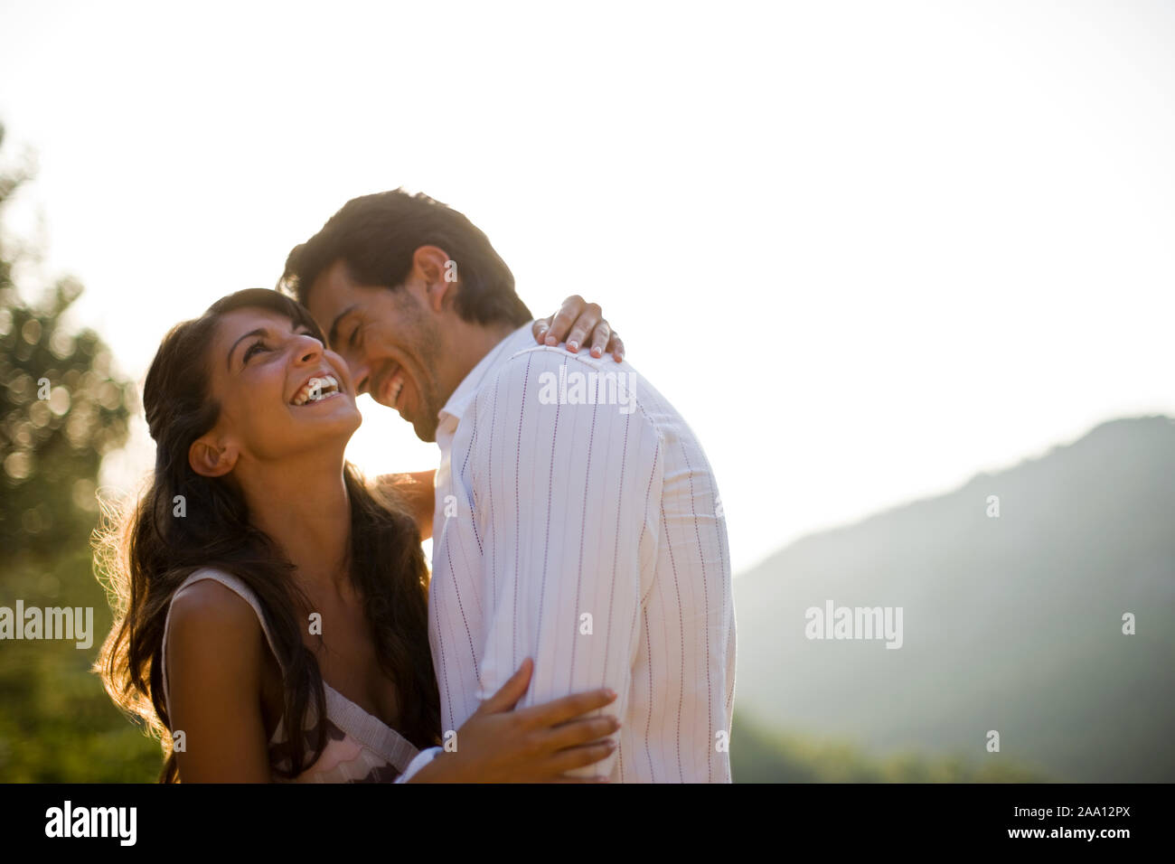 Mid adult couple hugging while walking on a country lane at sunset ...