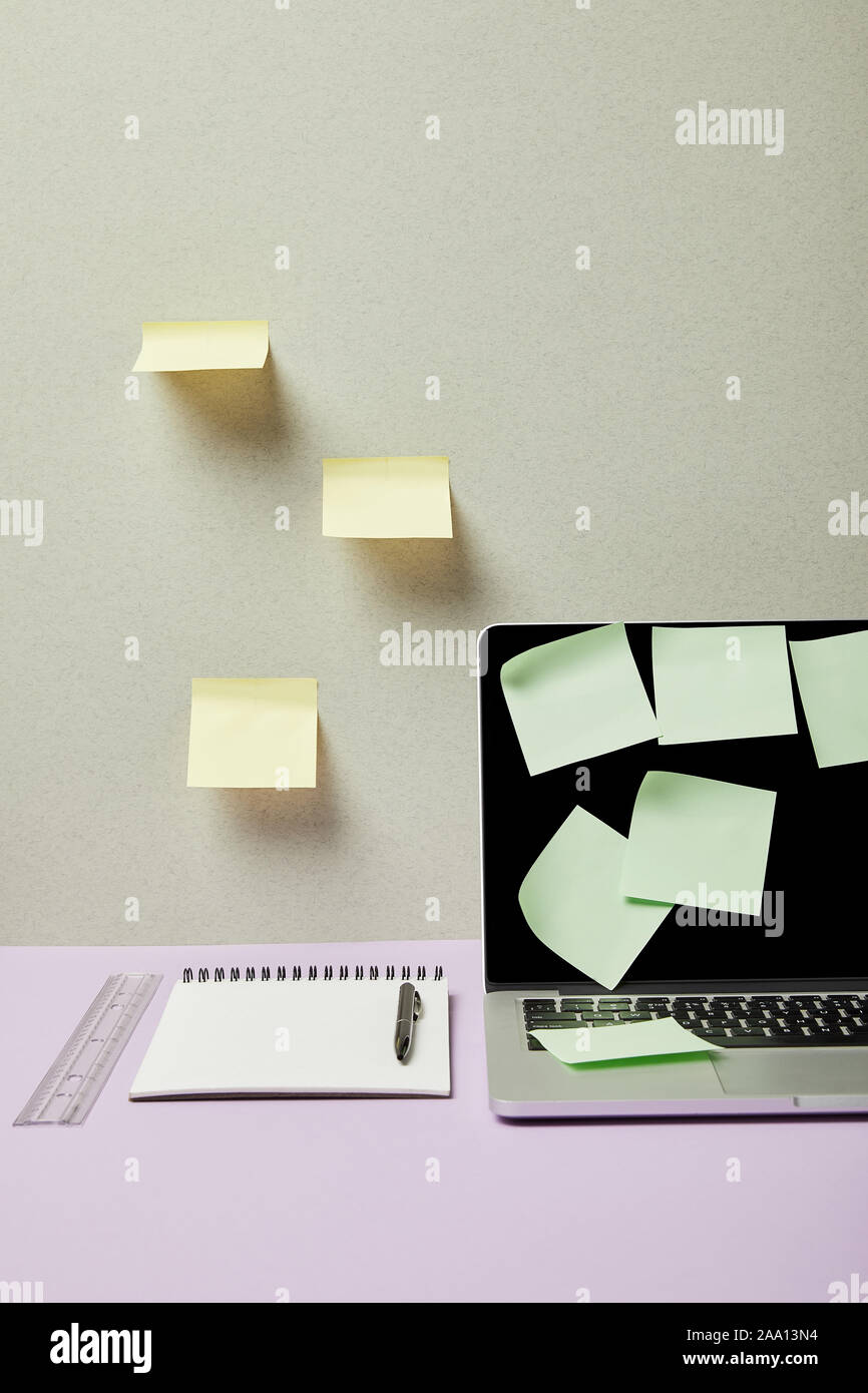 green sticky notes on laptop near notebook, ruler and pen on grey and ...