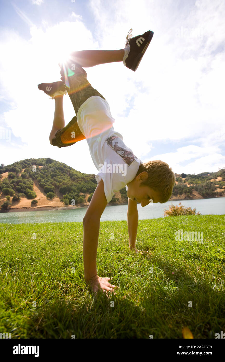 Boy doing a handstand on a grassy lawn near a lake Stock Photo - Alamy