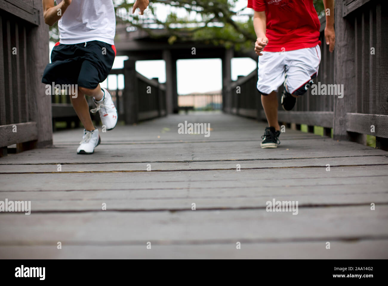 Legs of two boys running along a wooden walkway Stock Photo - Alamy