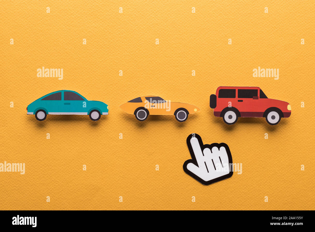 top view of paper cut cars with pointing hand on orange background ...
