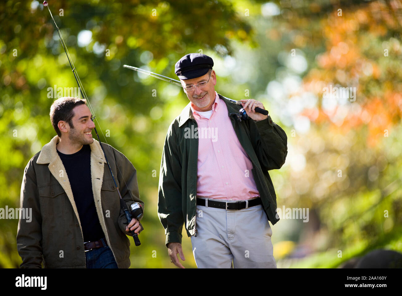 Two men holding fishing rods and taking a stroll Stock Photo - Alamy