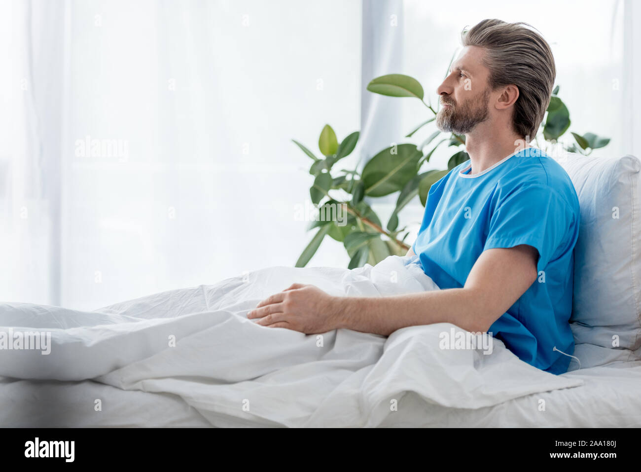 side view of patient in medical gown sitting on bed in hospital Stock ...