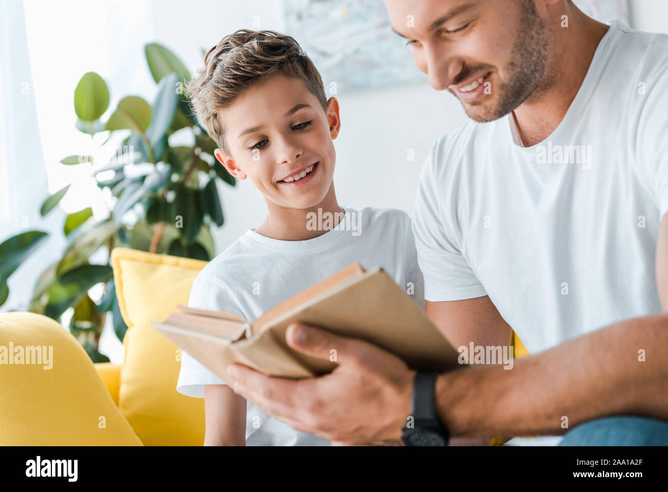 selective focus of happy father reading book near kid Stock Photo - Alamy