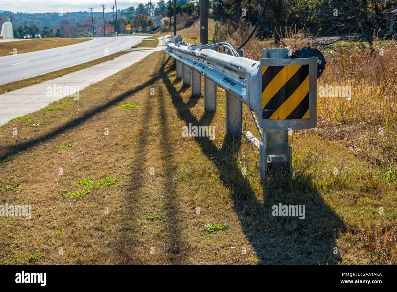 Alongside a four lane highway is a sturdy metal guardrail with a ...