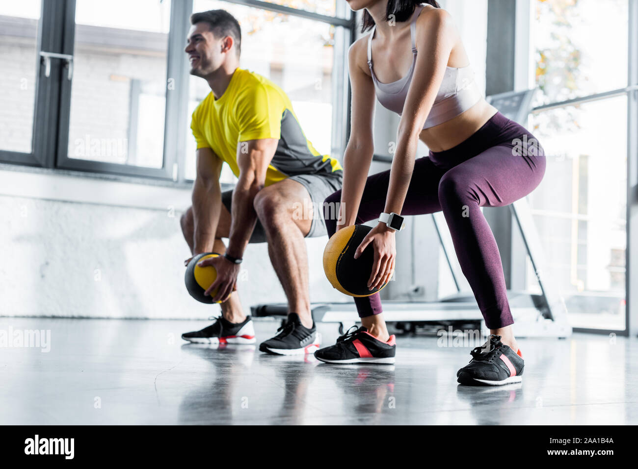 sportsman and sportswoman doing squat with balls in sports center Stock ...