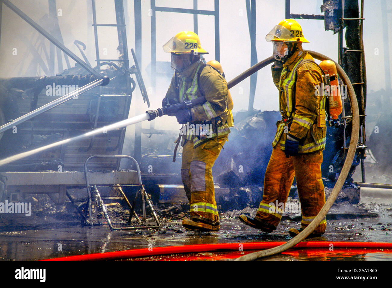 Wearing helmets, coats and air masks, a fireman and his partner spray ...