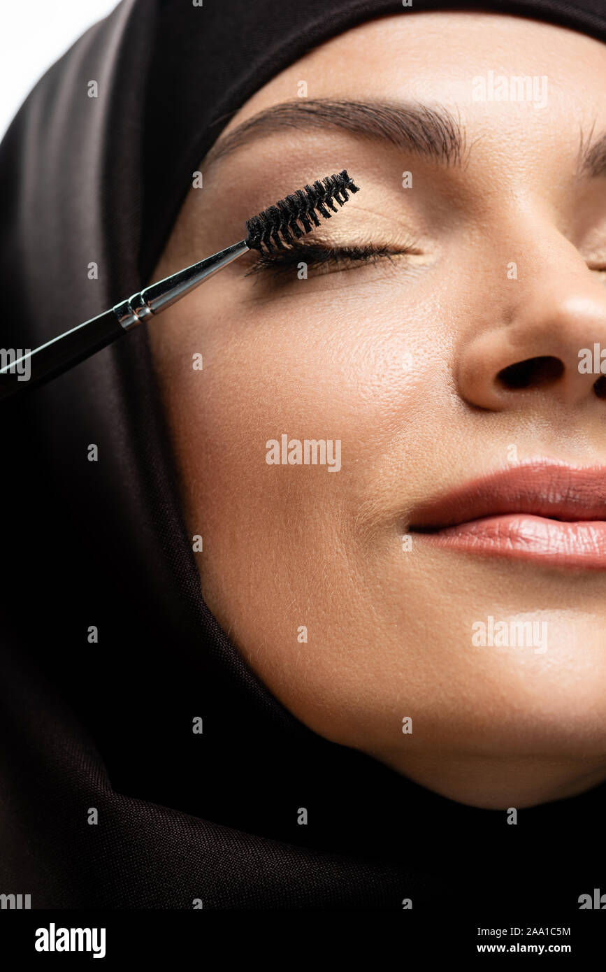 close up view of young Muslim woman in hijab applying mascara on ...