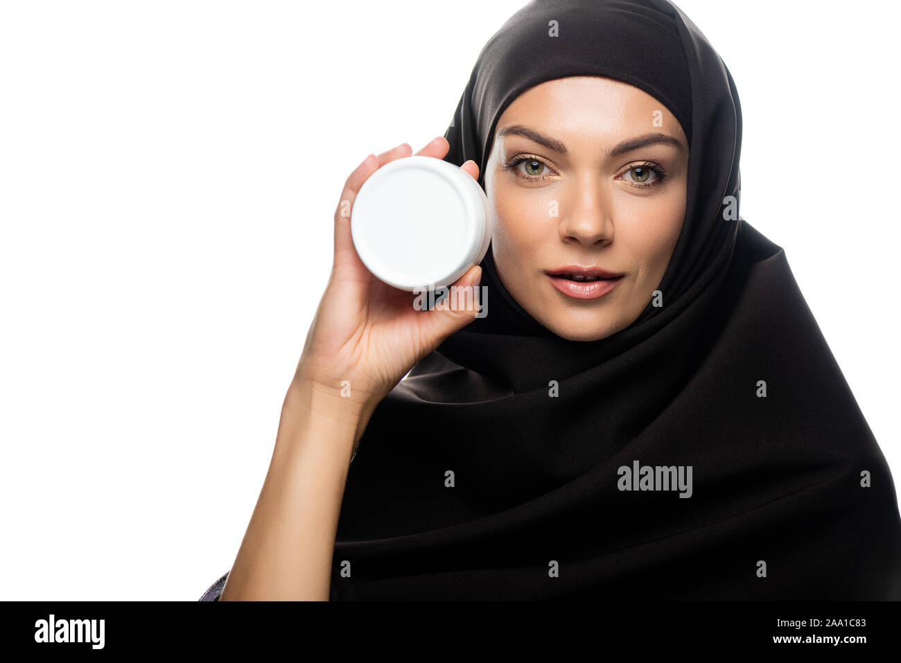 young Muslim woman in hijab holding container with cosmetic cream ...