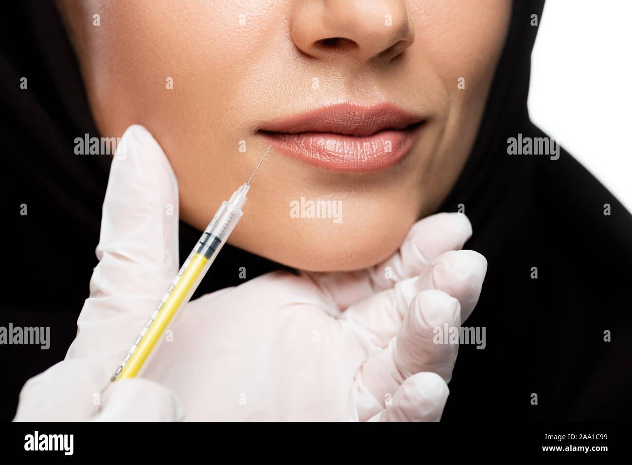 cropped view of young Muslim woman in hijab having beauty injection ...