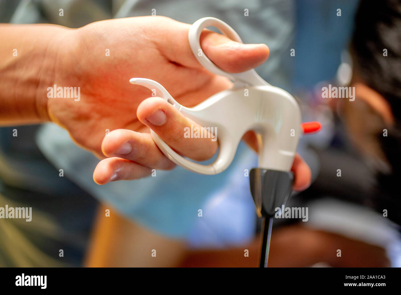 An Asian American doctor's hand manipulates remote control laproscopic ...