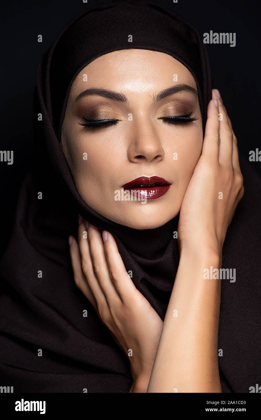 young Muslim woman in hijab with closed eyes, smoky eyes and red lips ...