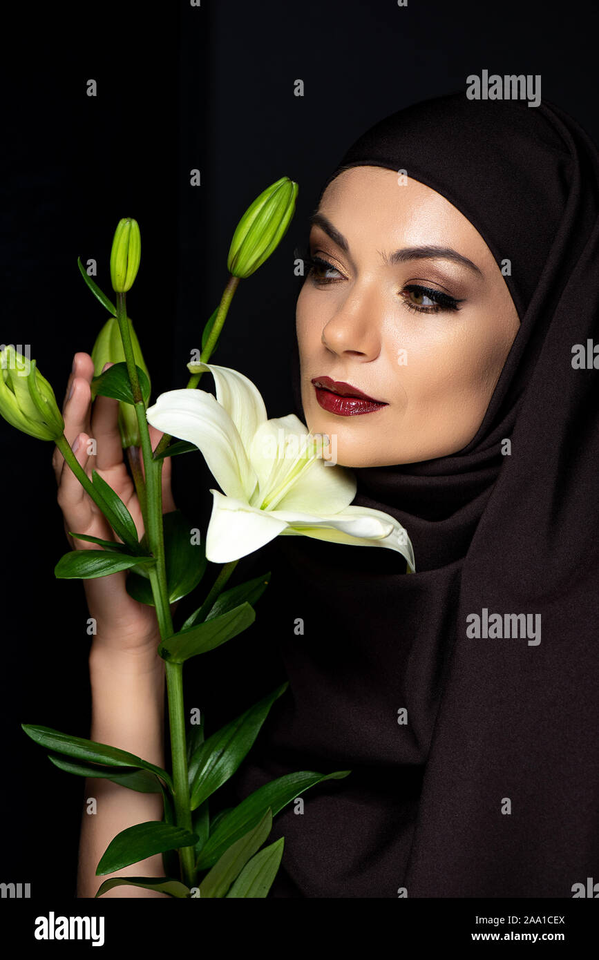attractive Muslim woman in hijab with red lips holding lily isolated on ...