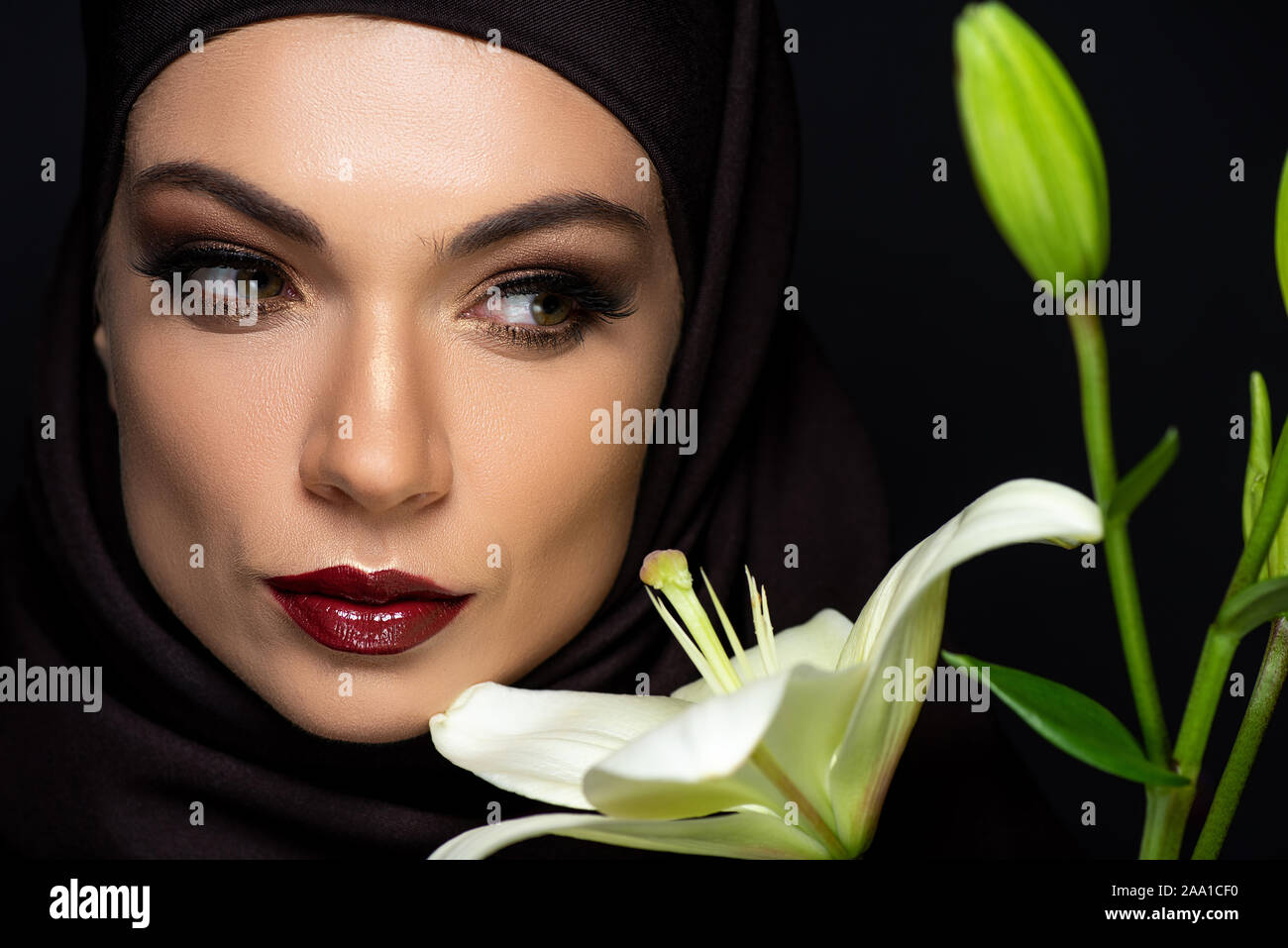 attractive Muslim woman in hijab with red lips near lily isolated on ...