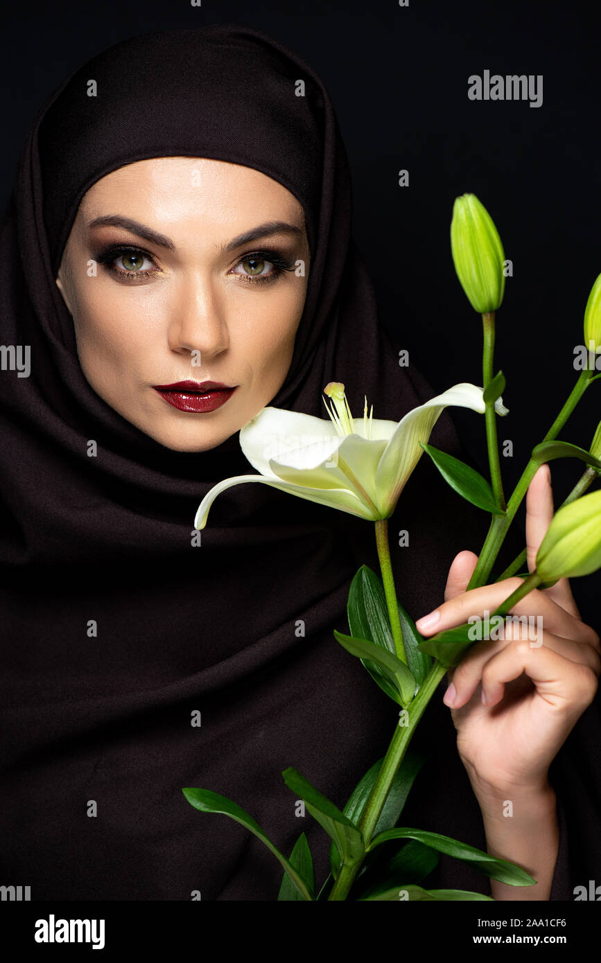 attractive Muslim woman in hijab with red lips holding lily isolated on ...
