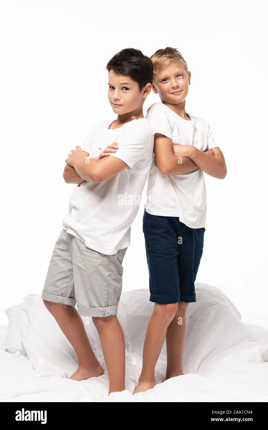 two cunning boys standing back to back with crossed arms and smiling at ...