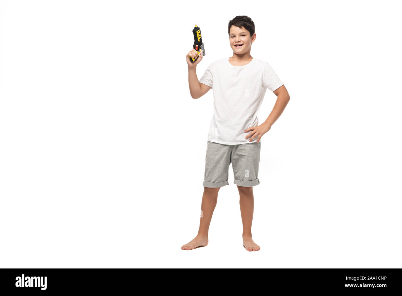 cheerful boy holding toy gun while standing with hands on hips and ...