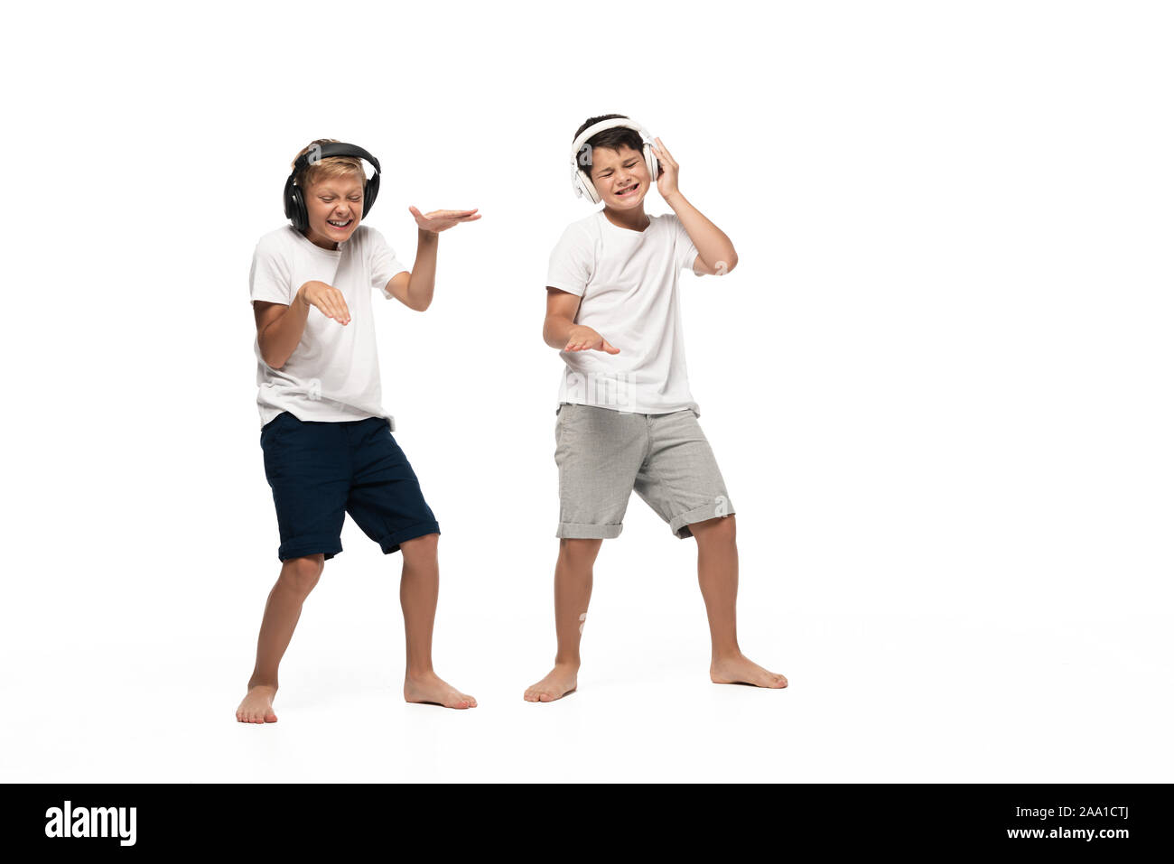 two cheerful brothers listening music in headphones and dancing on ...