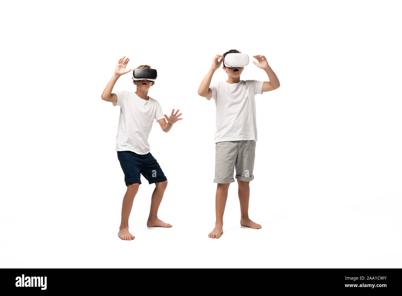 two scared brothers gesturing while using vr headsets on white ...