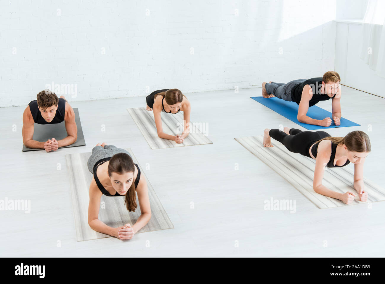 five young people practicing yoga in forearm plank pose Stock Photo - Alamy