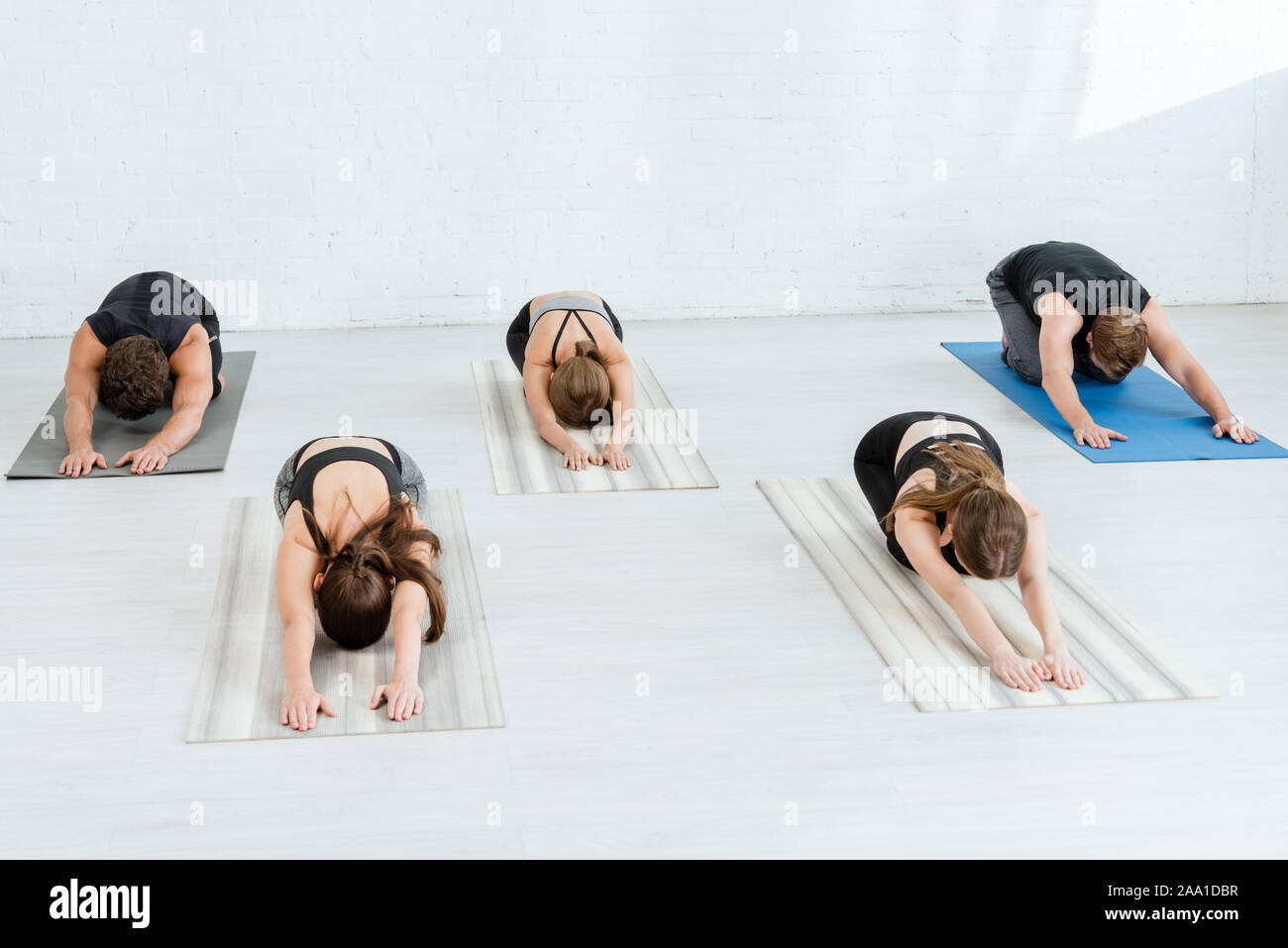 five young people practicing yoga in extended childs pose Stock Photo ...